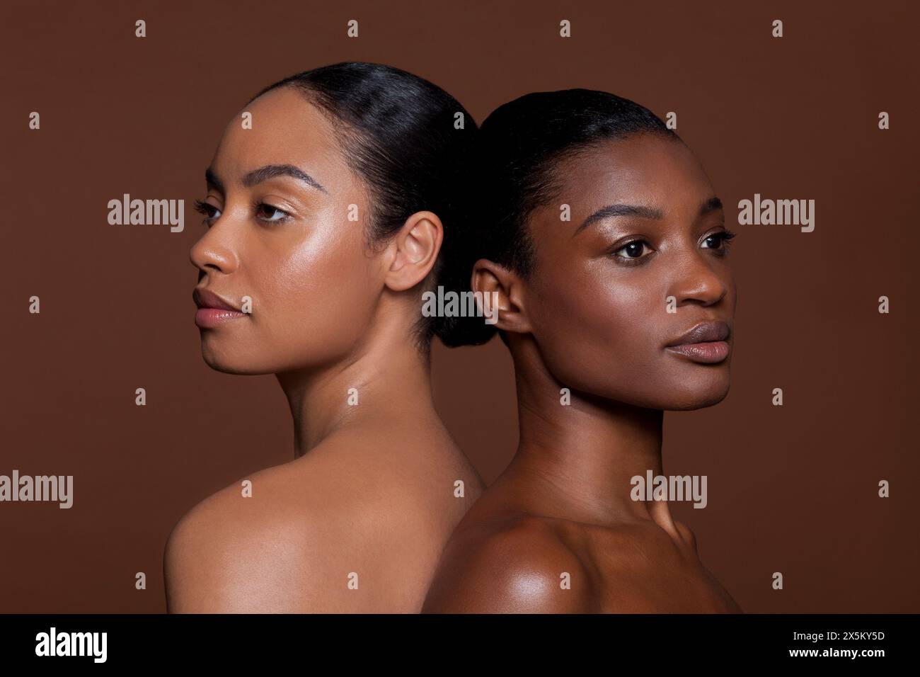 Young women standing back to back Stock Photo - Alamy