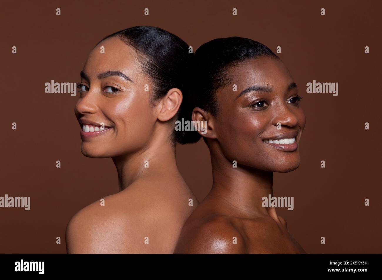 Portrait of young women standing back to back Stock Photo - Alamy