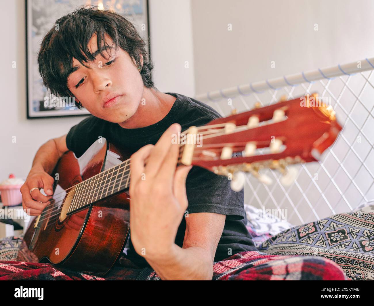Teenage boy playing acoustic guitar on bed Stock Photo - Alamy