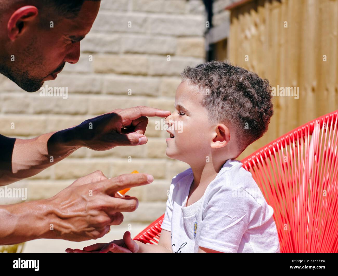 Father applying sun cream on sons face outdoors Stock Photo - Alamy
