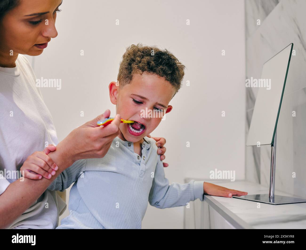 Mother helping son brushing teeth in bathroom Stock Photo - Alamy