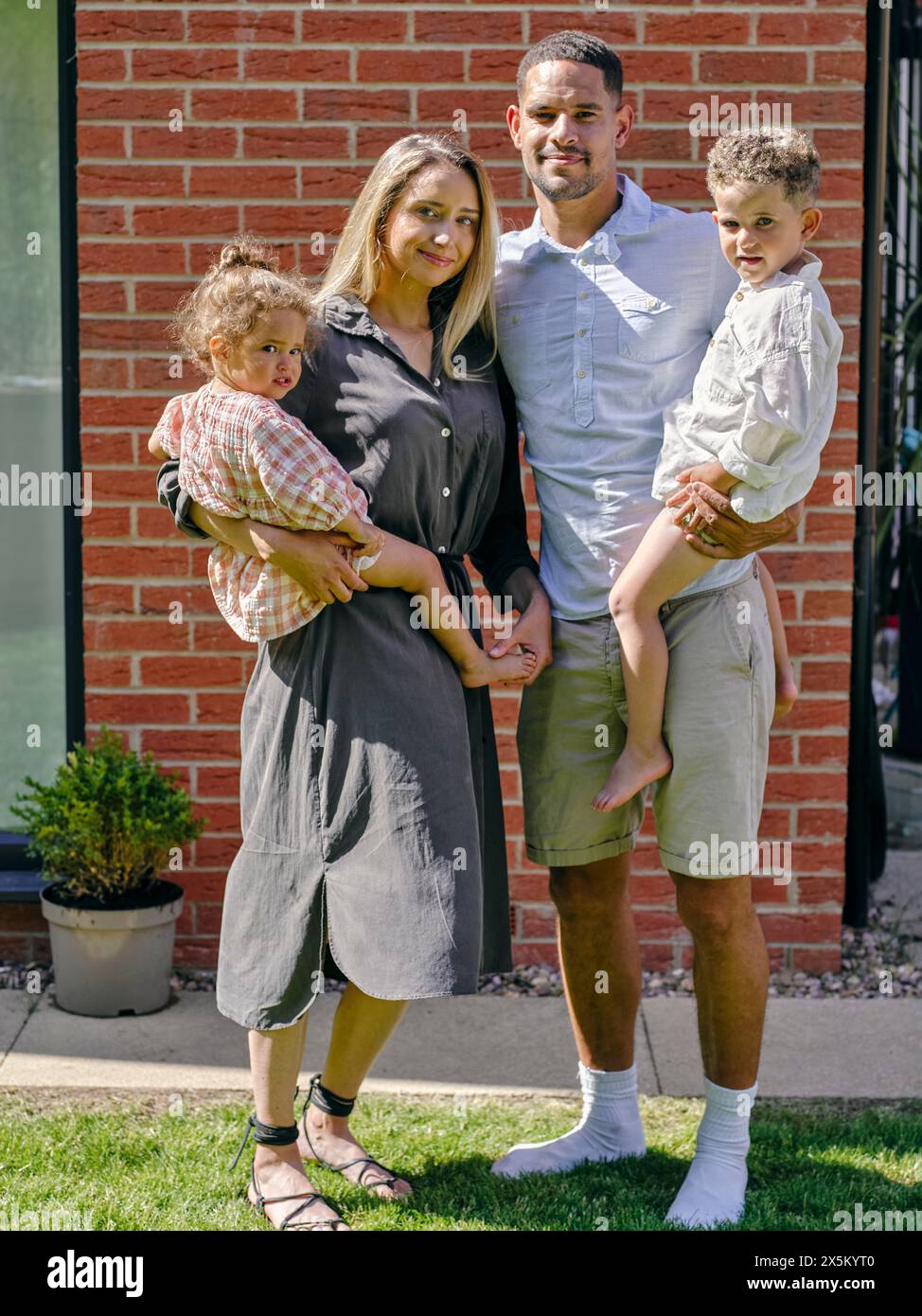 Portrait of parents with two children in front of house Stock Photo - Alamy