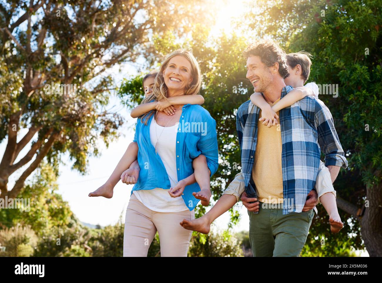 Family, happy and piggyback in forest with love for bonding, weekend ...