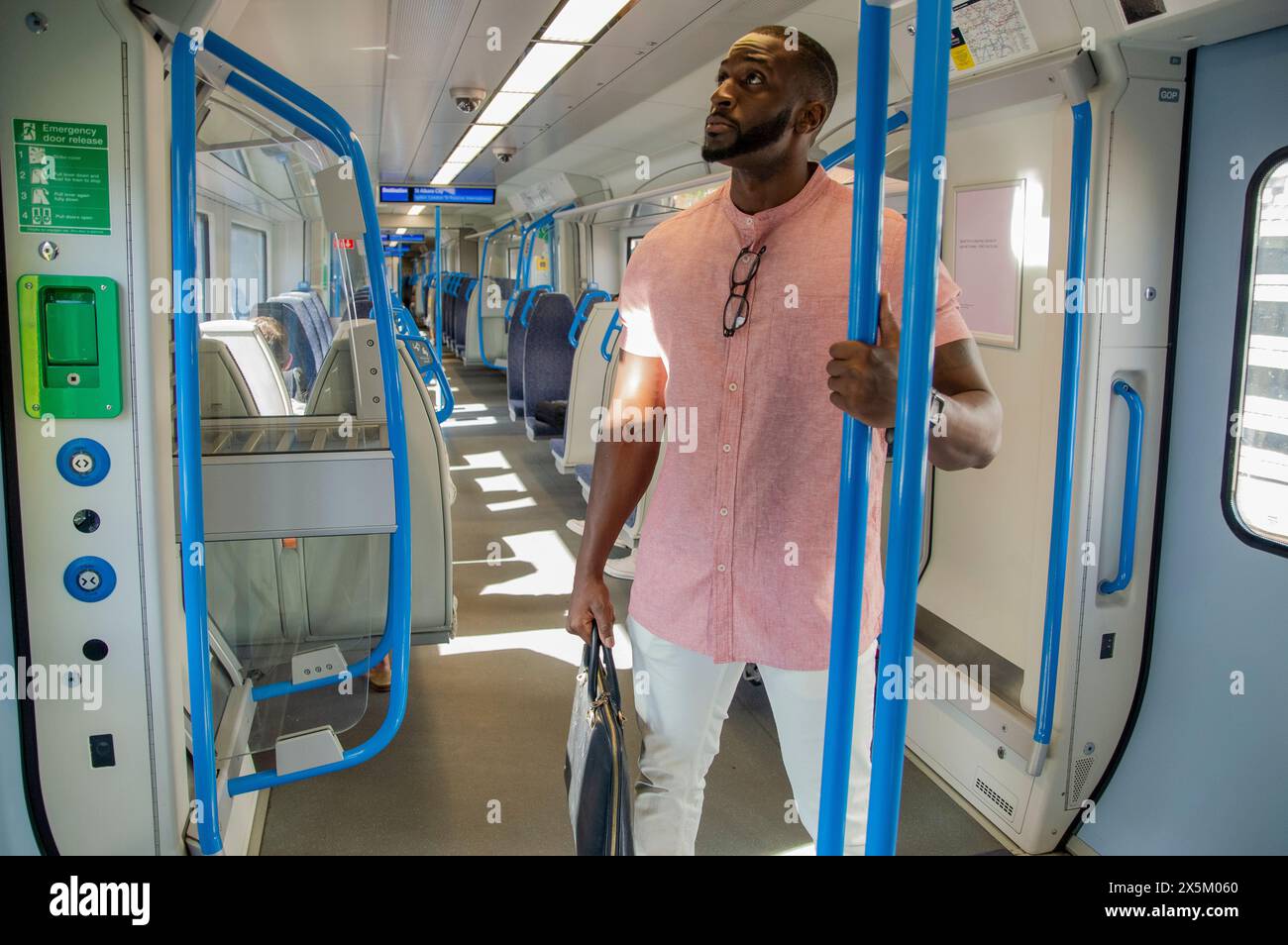 Man holding rail while standing in passenger train Stock Photo - Alamy