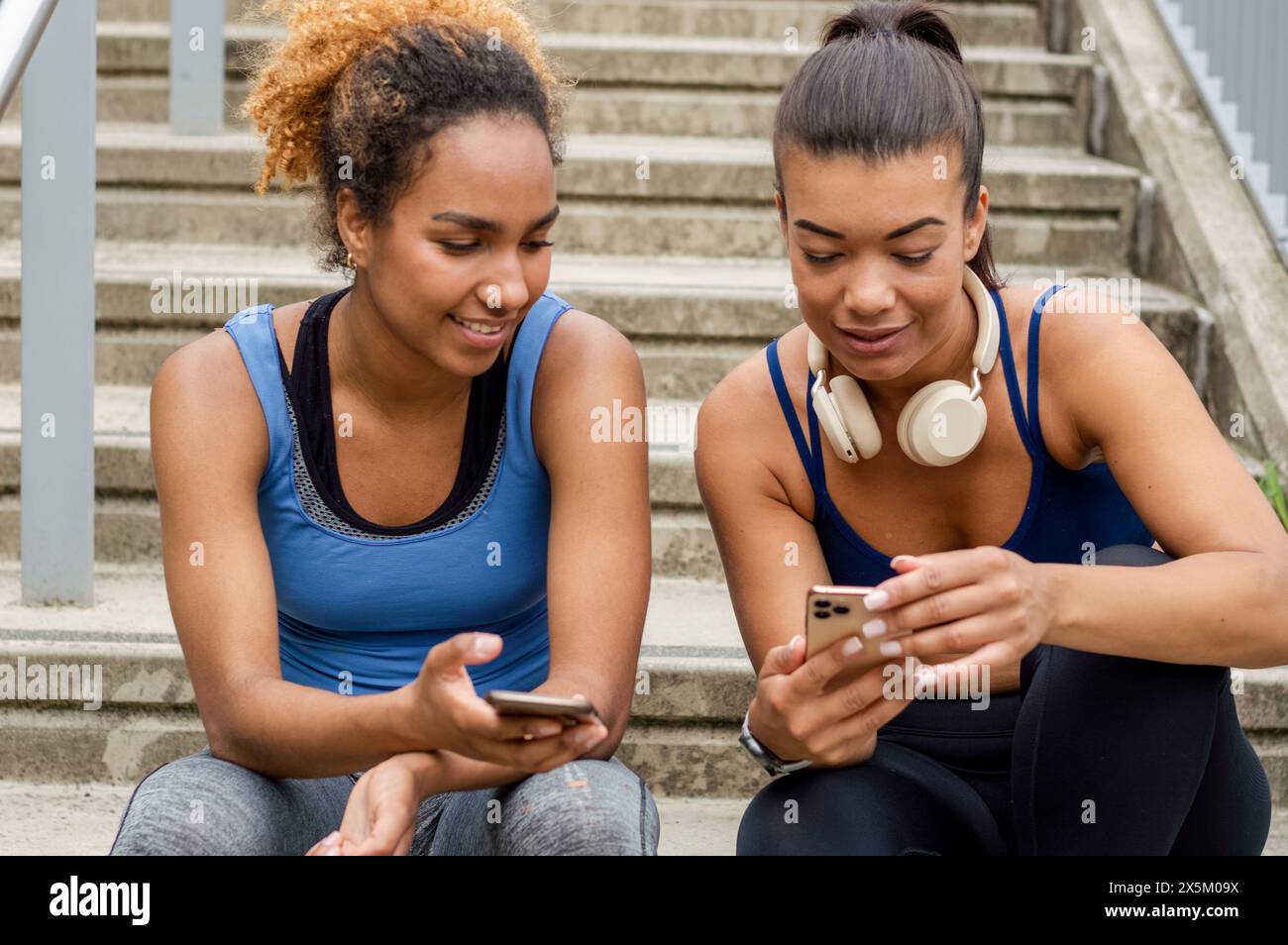 Sporty female friends using phones Stock Photo - Alamy
