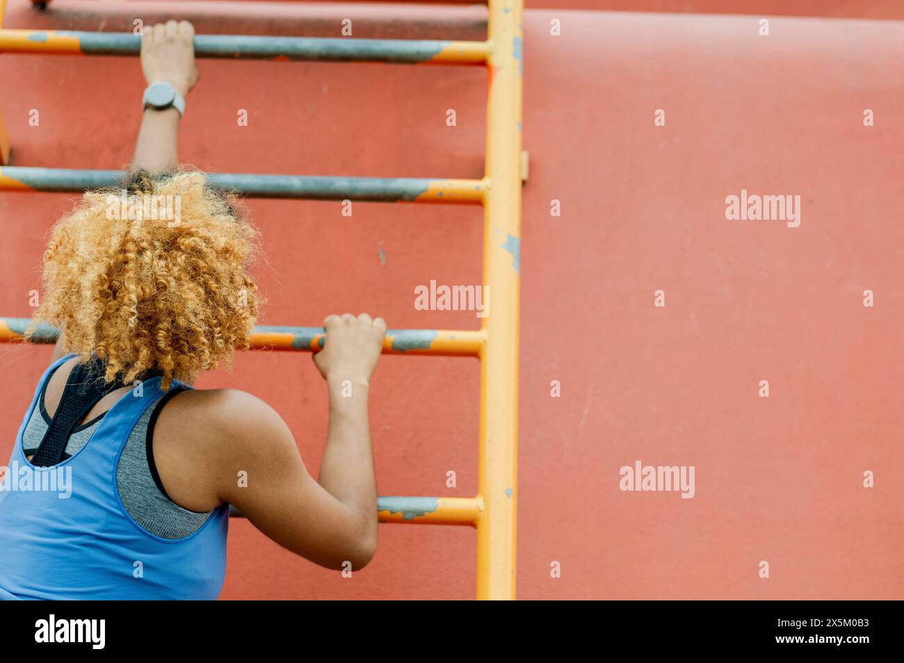Sporty young woman climbing ladder Stock Photo - Alamy
