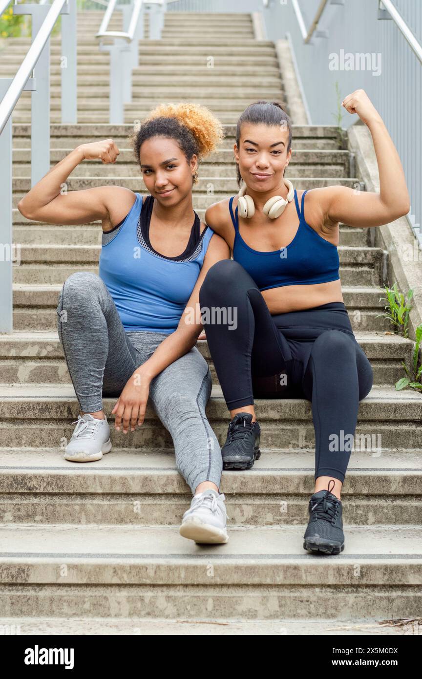 Portrait of female friends flexing biceps Stock Photo - Alamy