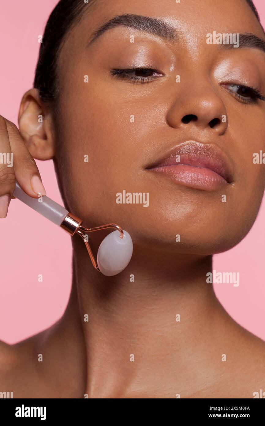 Young woman using rose quartz roller Stock Photo - Alamy