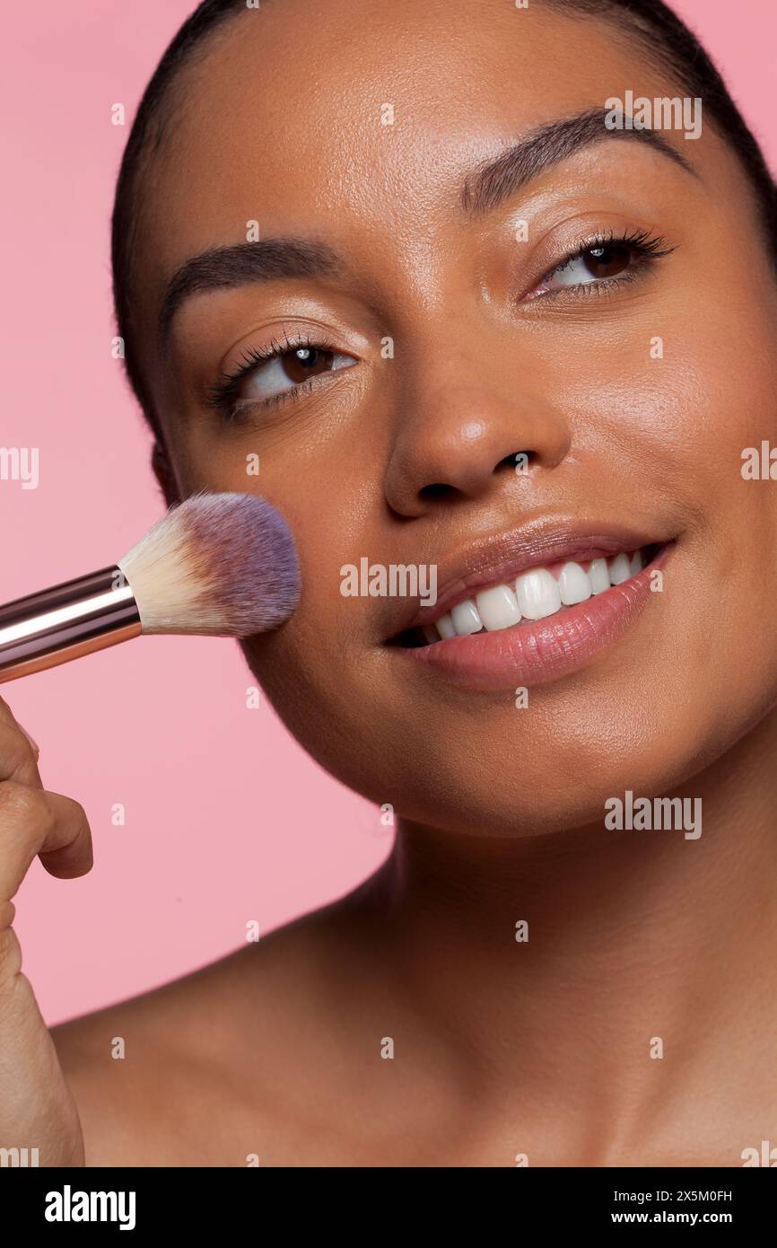 Studio portrait of smiling beautiful woman using powder brush Stock ...