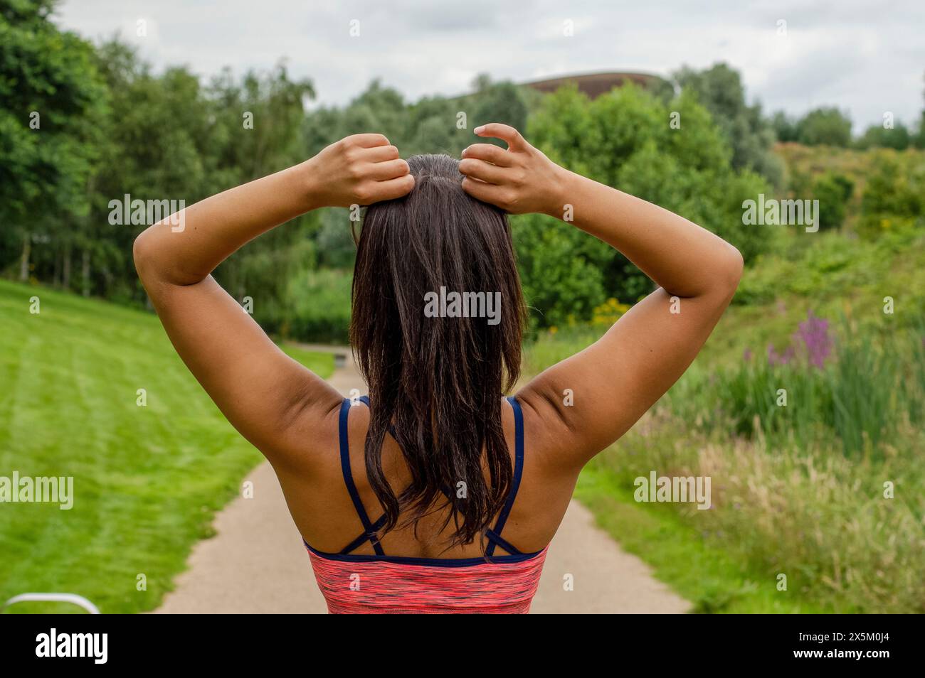 Rear view of woman tying hair before training Stock Photo - Alamy