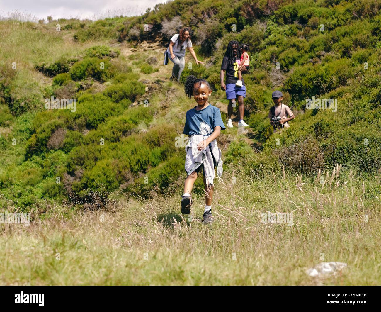 Family with three kids hiking in green hills Stock Photo - Alamy