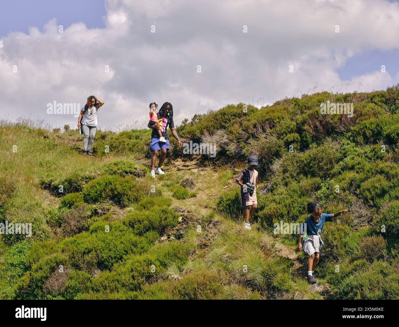Family with three kids hiking in green hills Stock Photo - Alamy