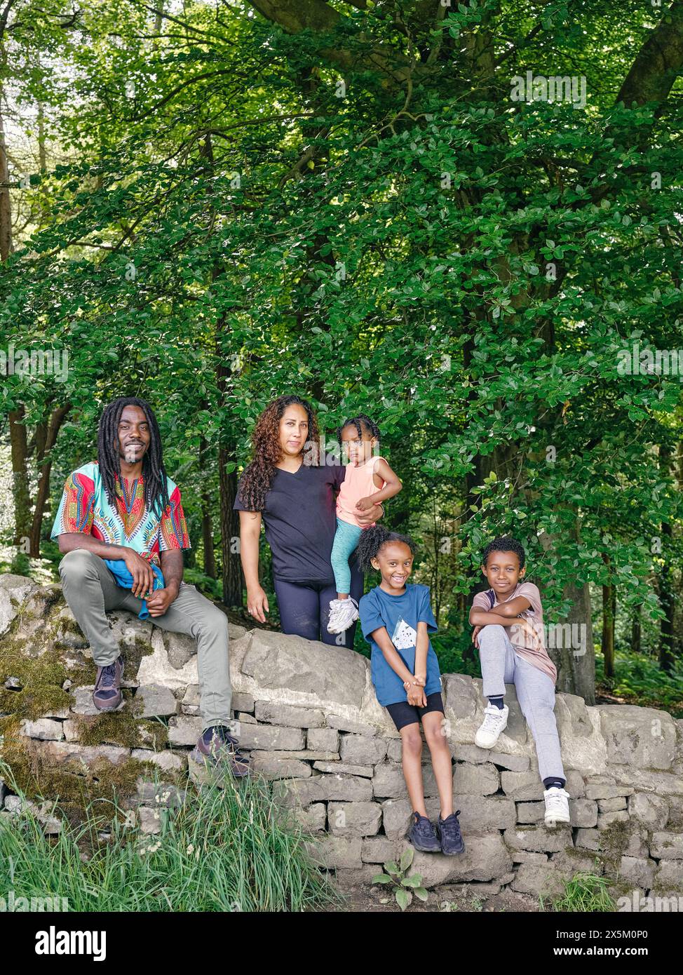 Family with children sitting on stone wall Stock Photo - Alamy