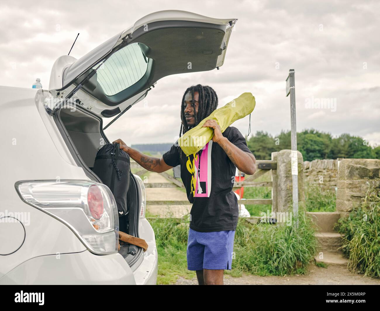 Man loading camping gear into car trunk Stock Photo - Alamy