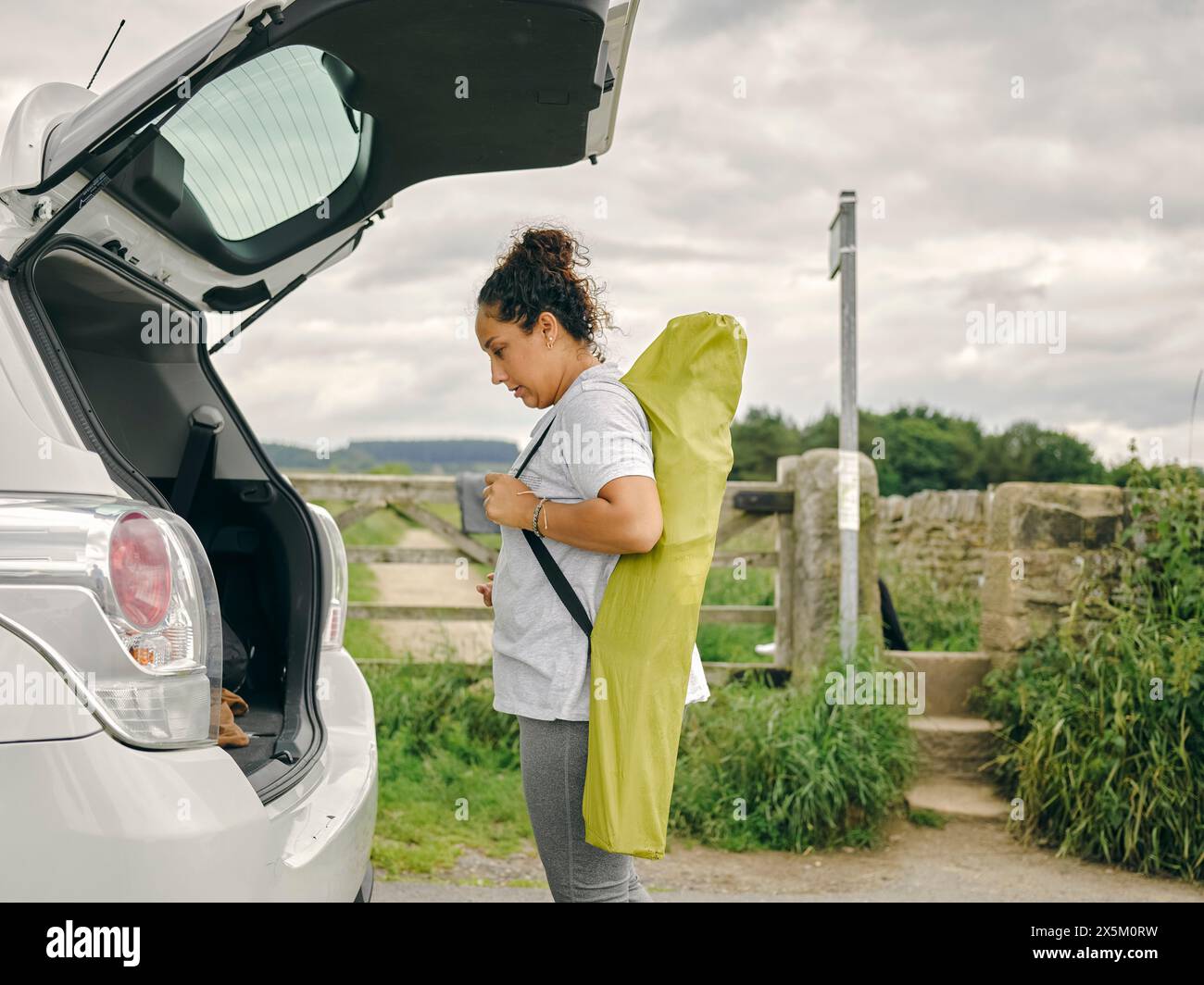 Woman loading camping gear into car trunk Stock Photo - Alamy