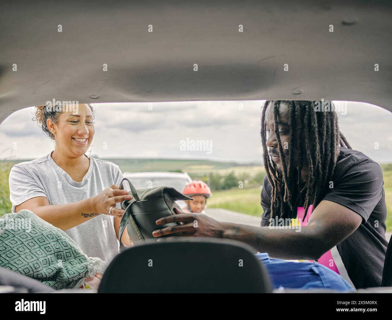 Couple putting luggage into car trunk Stock Photo - Alamy