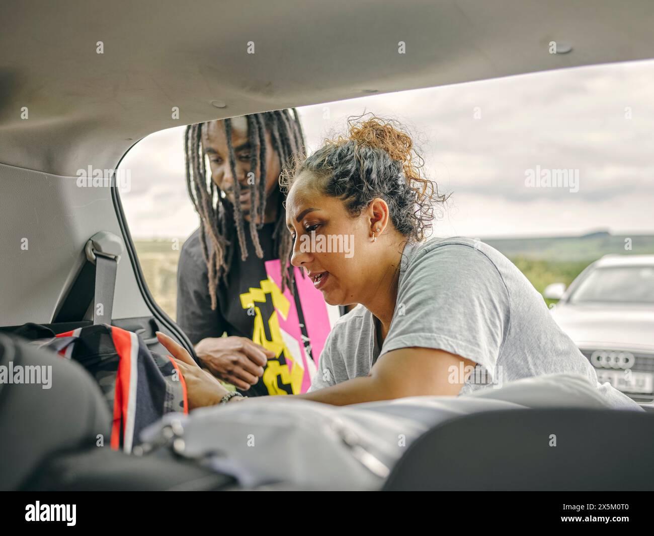 Couple putting luggage into car trunk Stock Photo - Alamy