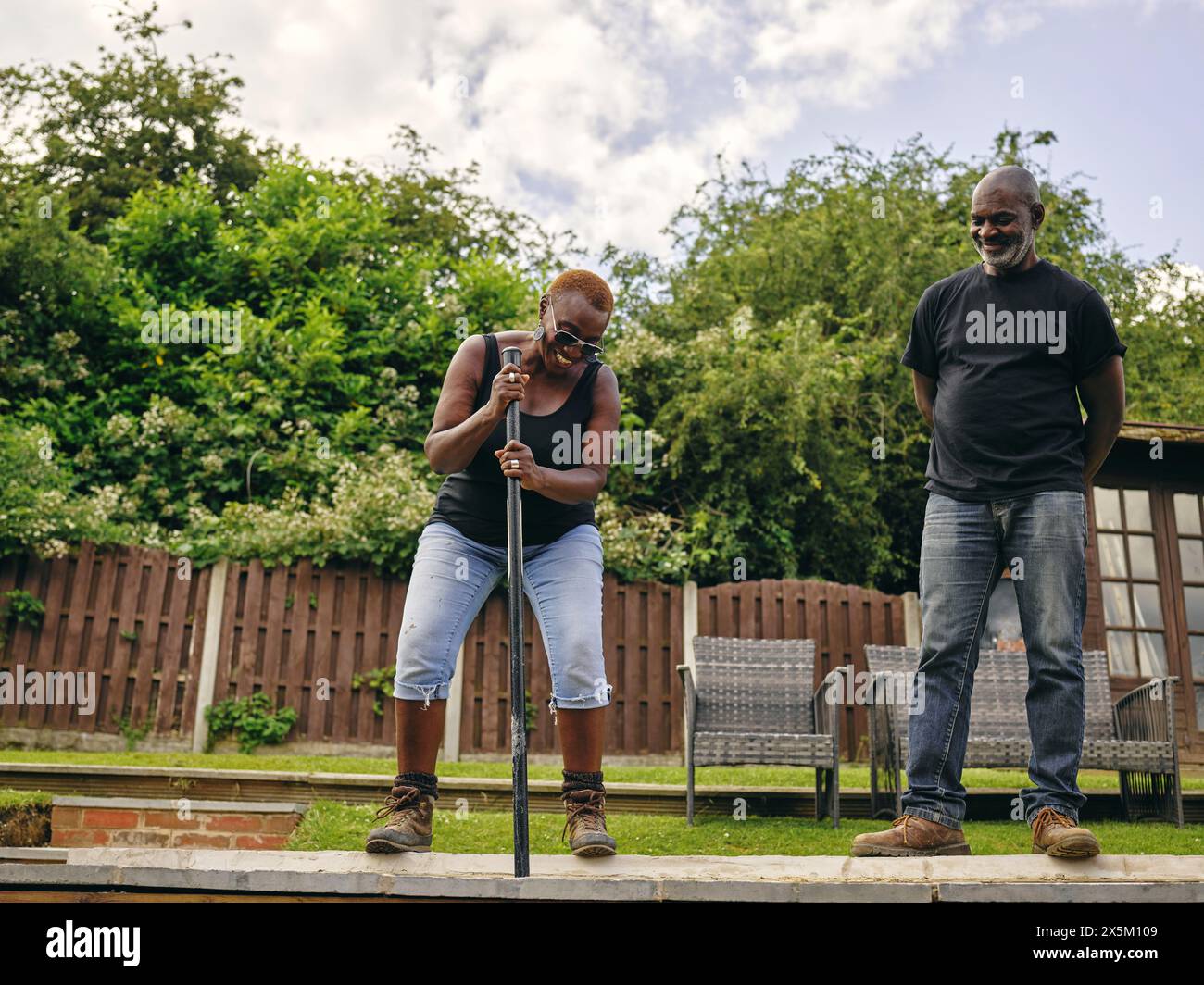Couple doing construction work in backyard Stock Photo - Alamy
