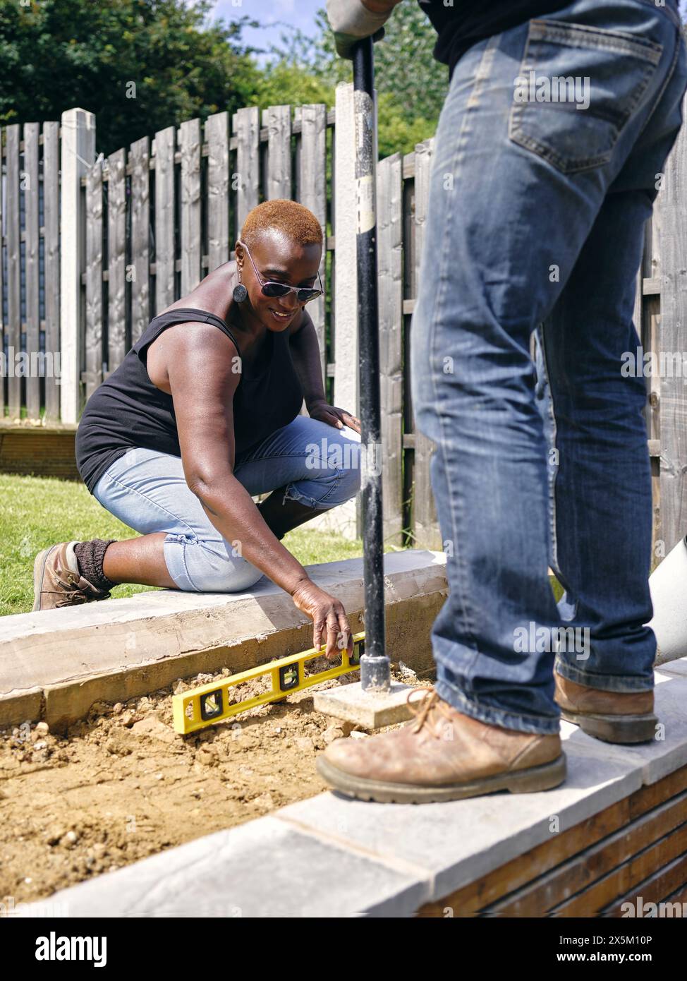 Couple doing construction work in backyard Stock Photo - Alamy