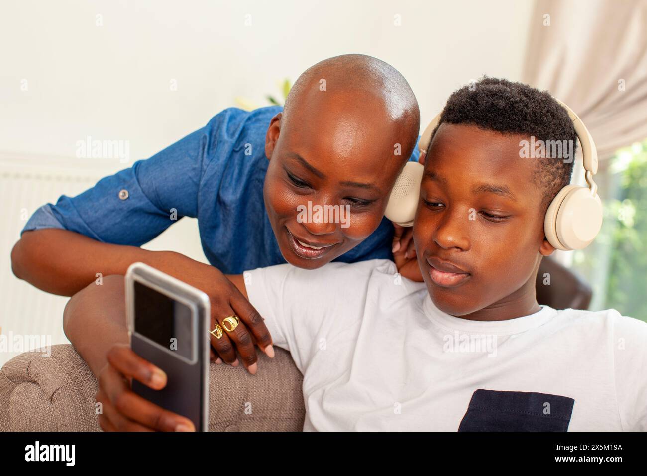 Mother and son using headphones and smart phone Stock Photo - Alamy