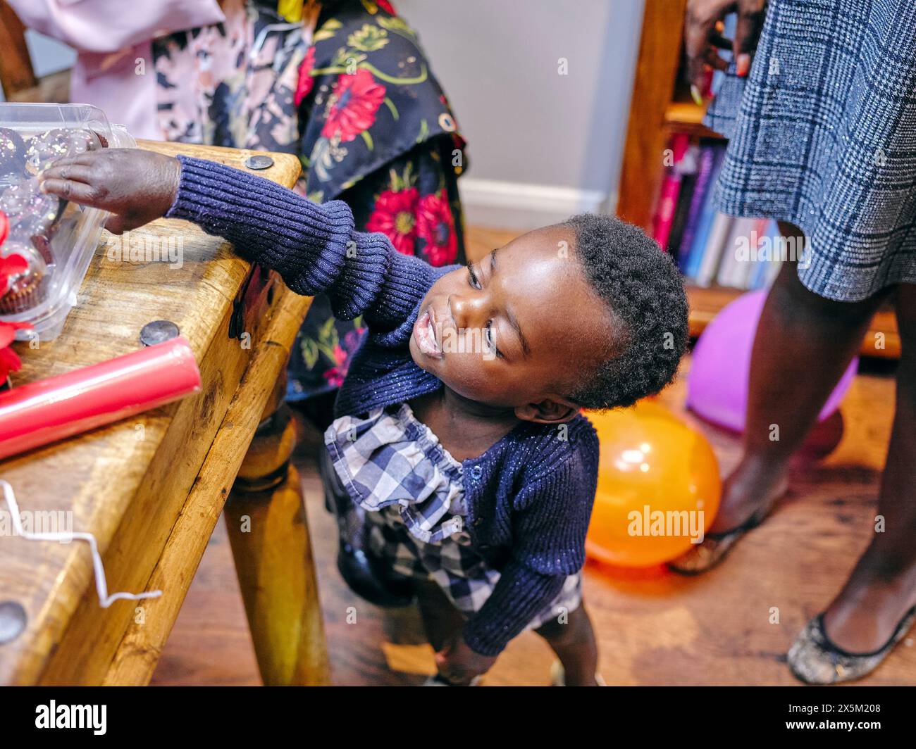 Baby girl reaching for box on table Stock Photo - Alamy