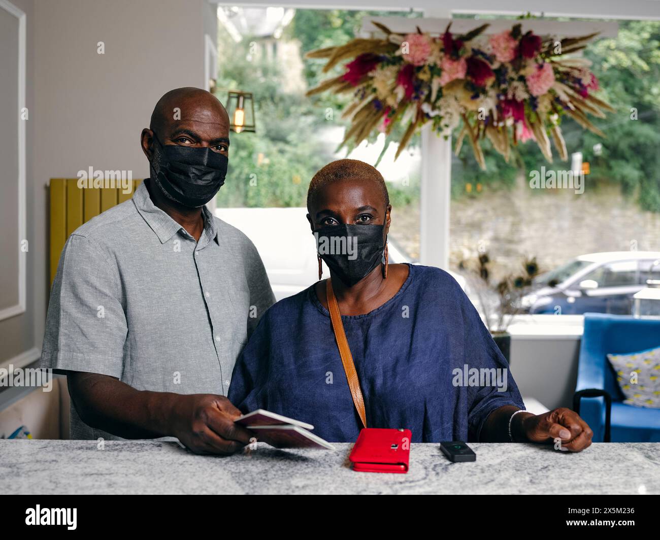 UK, Portrait of mature couple in face masks at hotel front desk Stock ...
