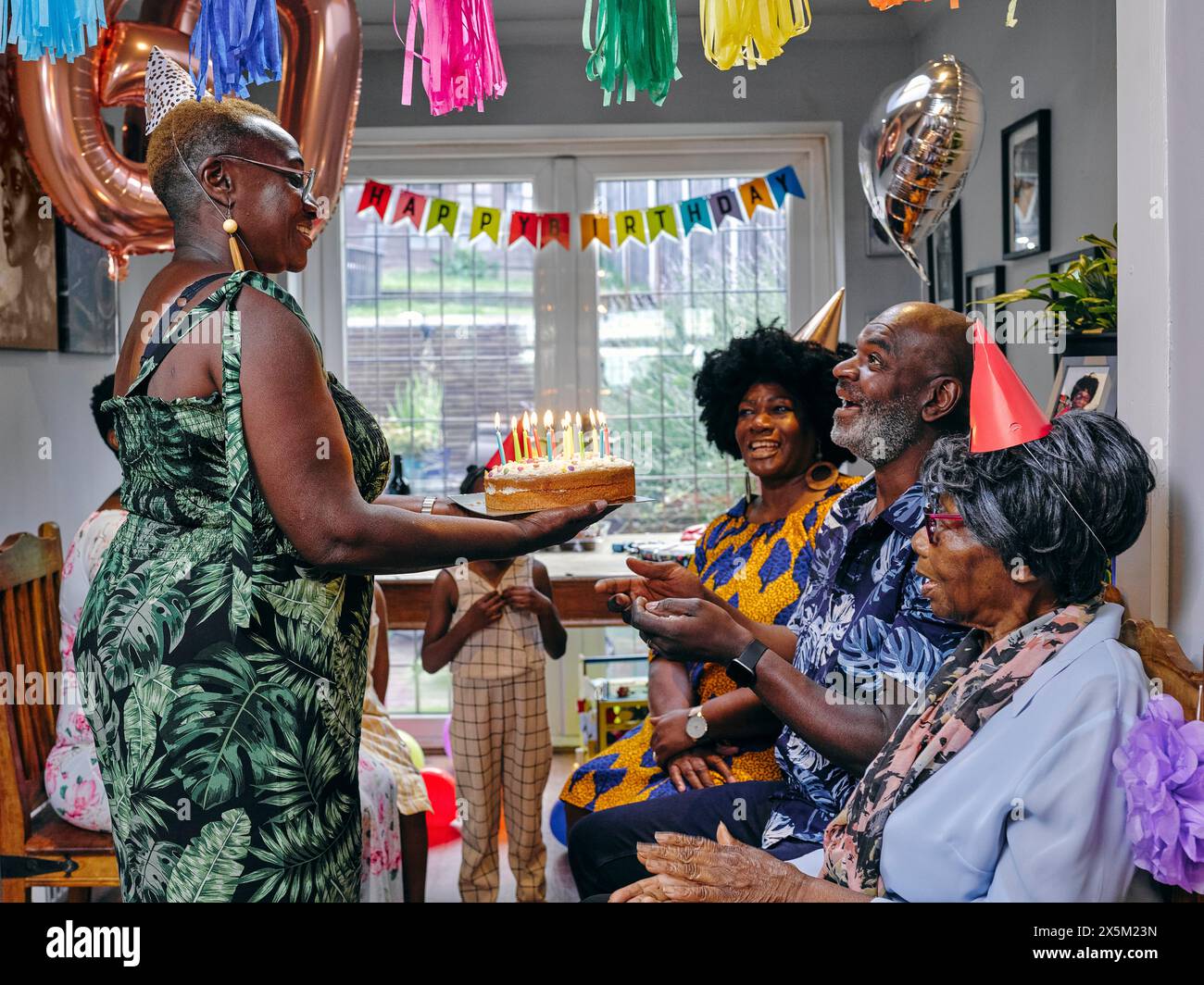 Multi-generation family celebrating birthday with birthday cake Stock ...
