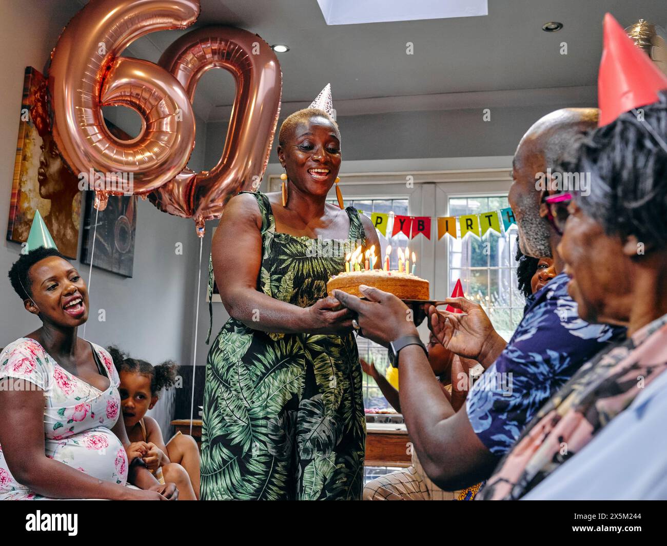 Woman giving man birthday cake at birthday party with family Stock ...