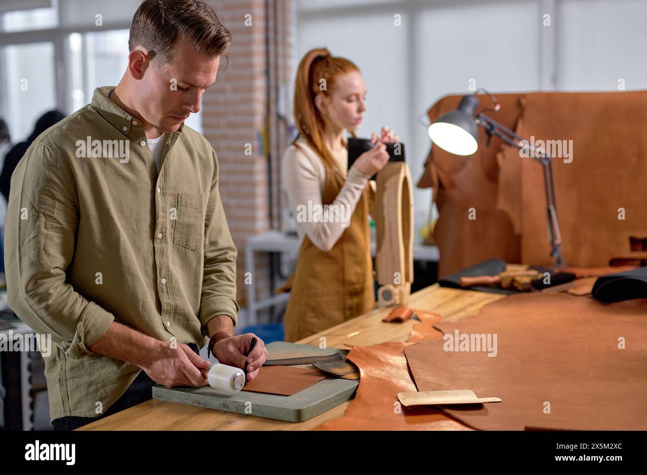 handsome male artsan marks holes in the leather., side view portrait ...