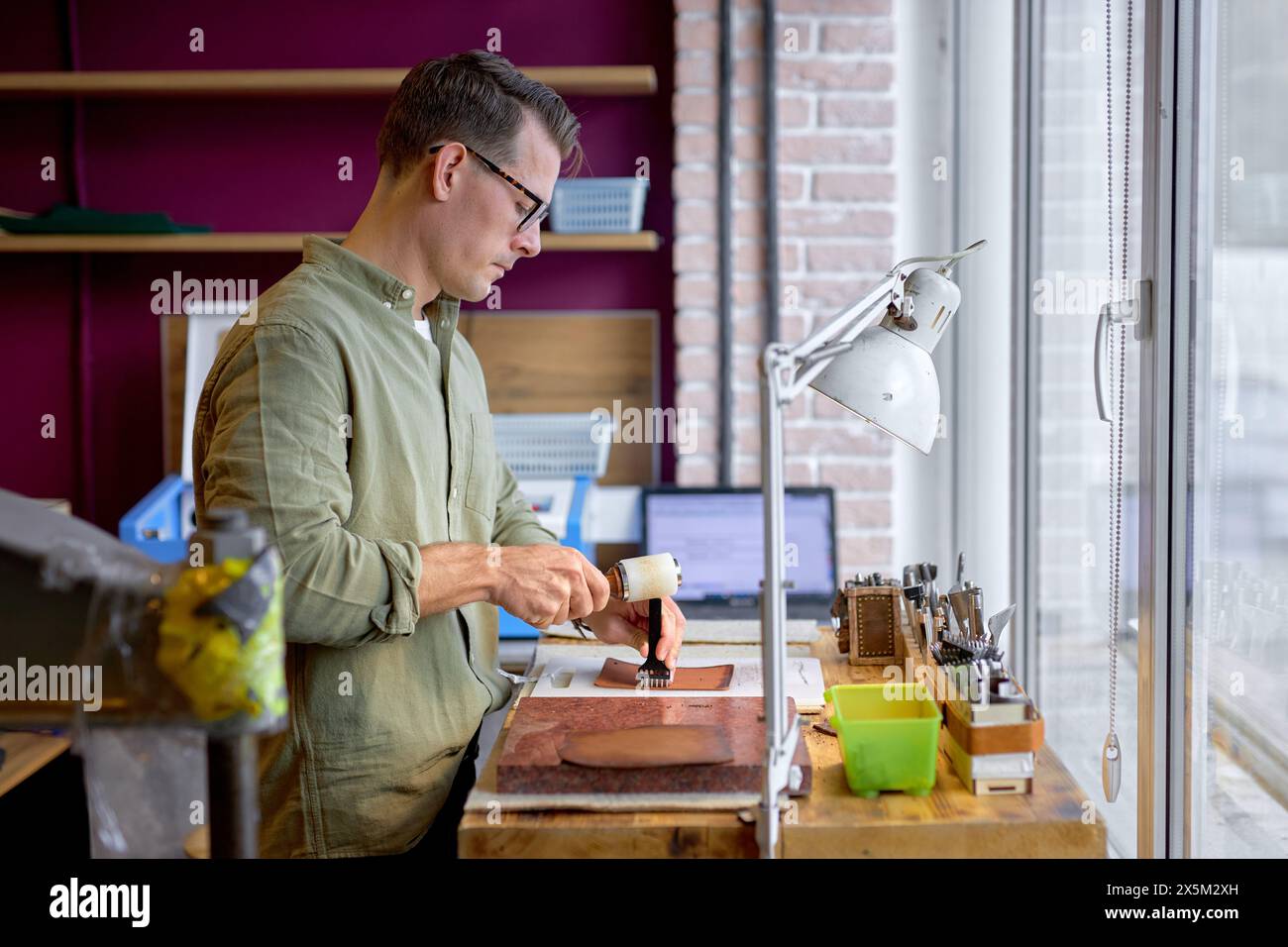 successful artisan using Stitching Punch and hammer, close up side view ...