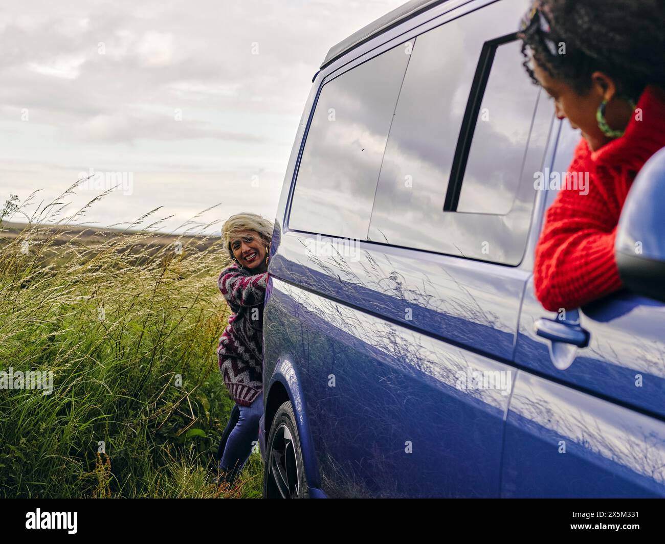 Woman pushing broken van Stock Photo - Alamy
