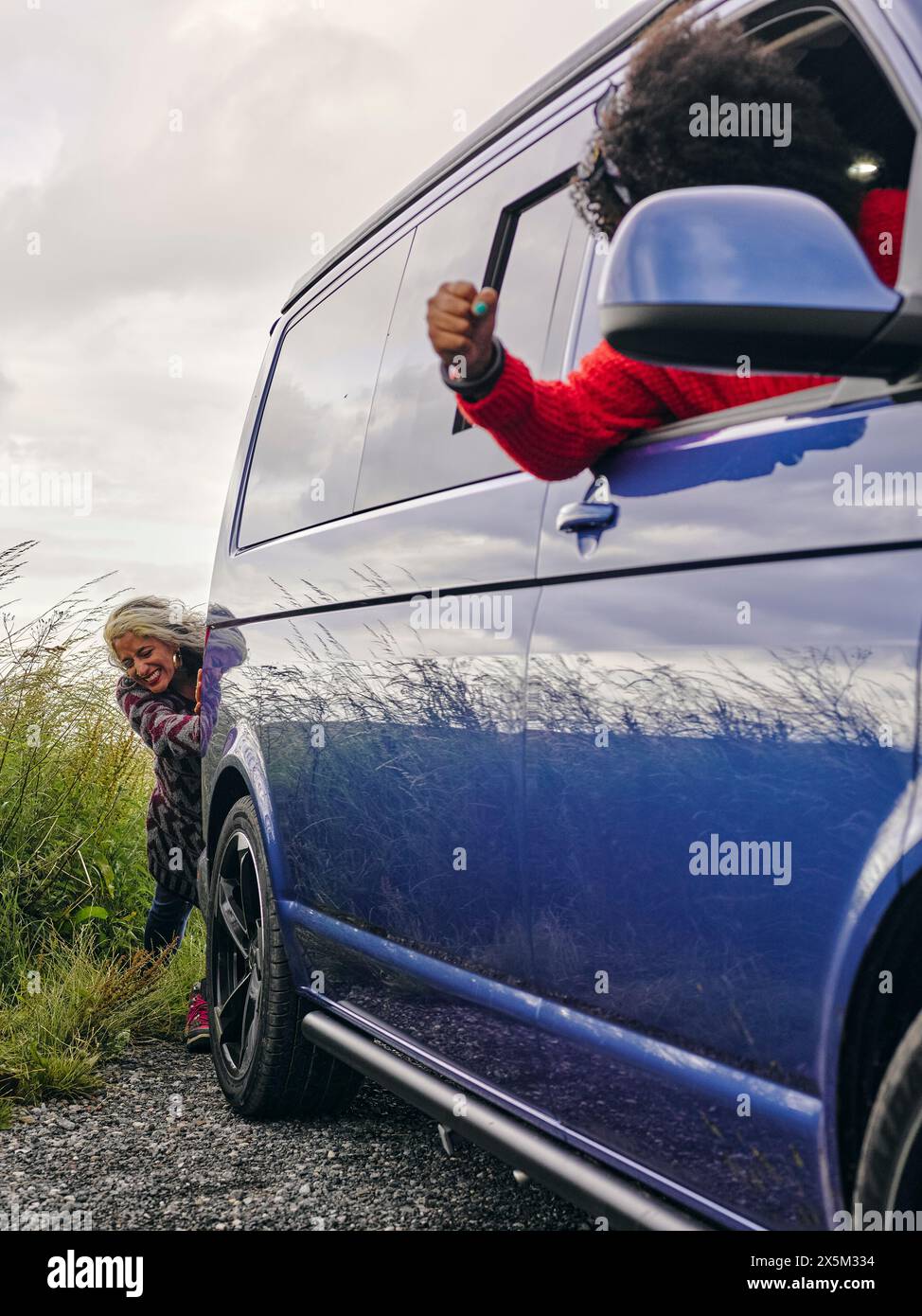 Woman pushing broken van Stock Photo - Alamy