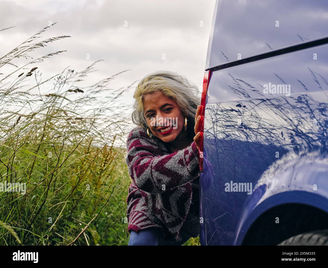 Woman pushing broken car Stock Photo - Alamy