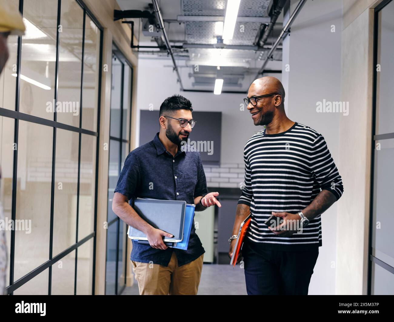 Two men talking in office hallway Stock Photo - Alamy