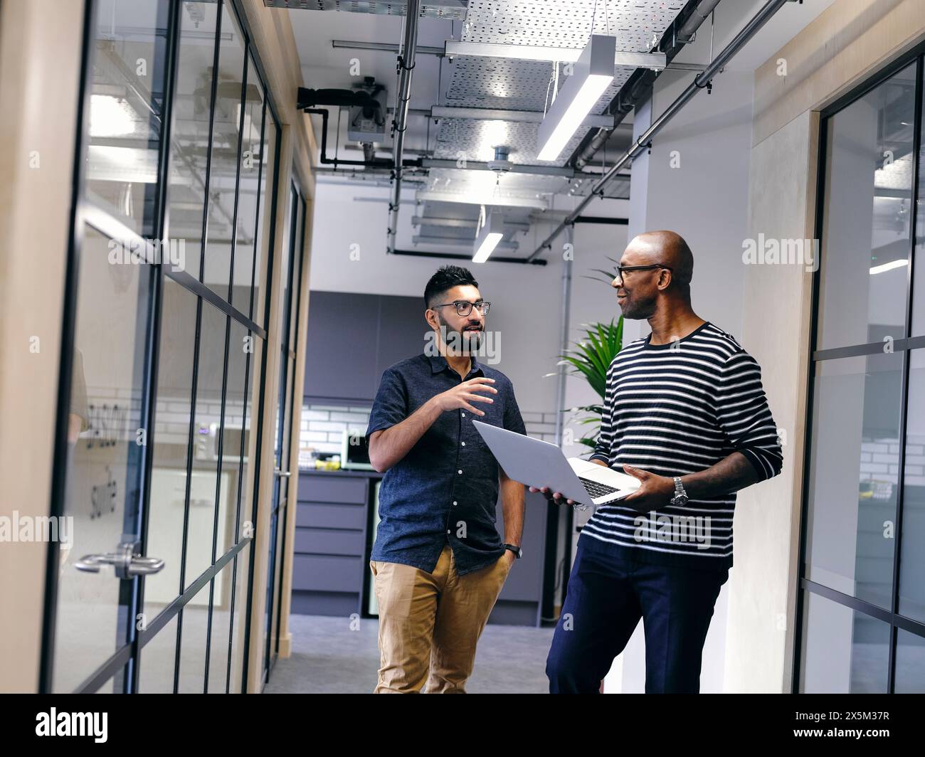 Two men talking in office hallway Stock Photo - Alamy