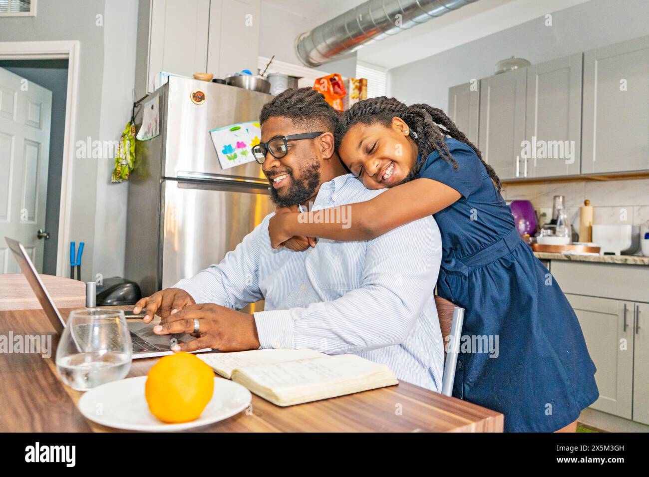 Girl hugging father working at home with laptop Stock Photo - Alamy