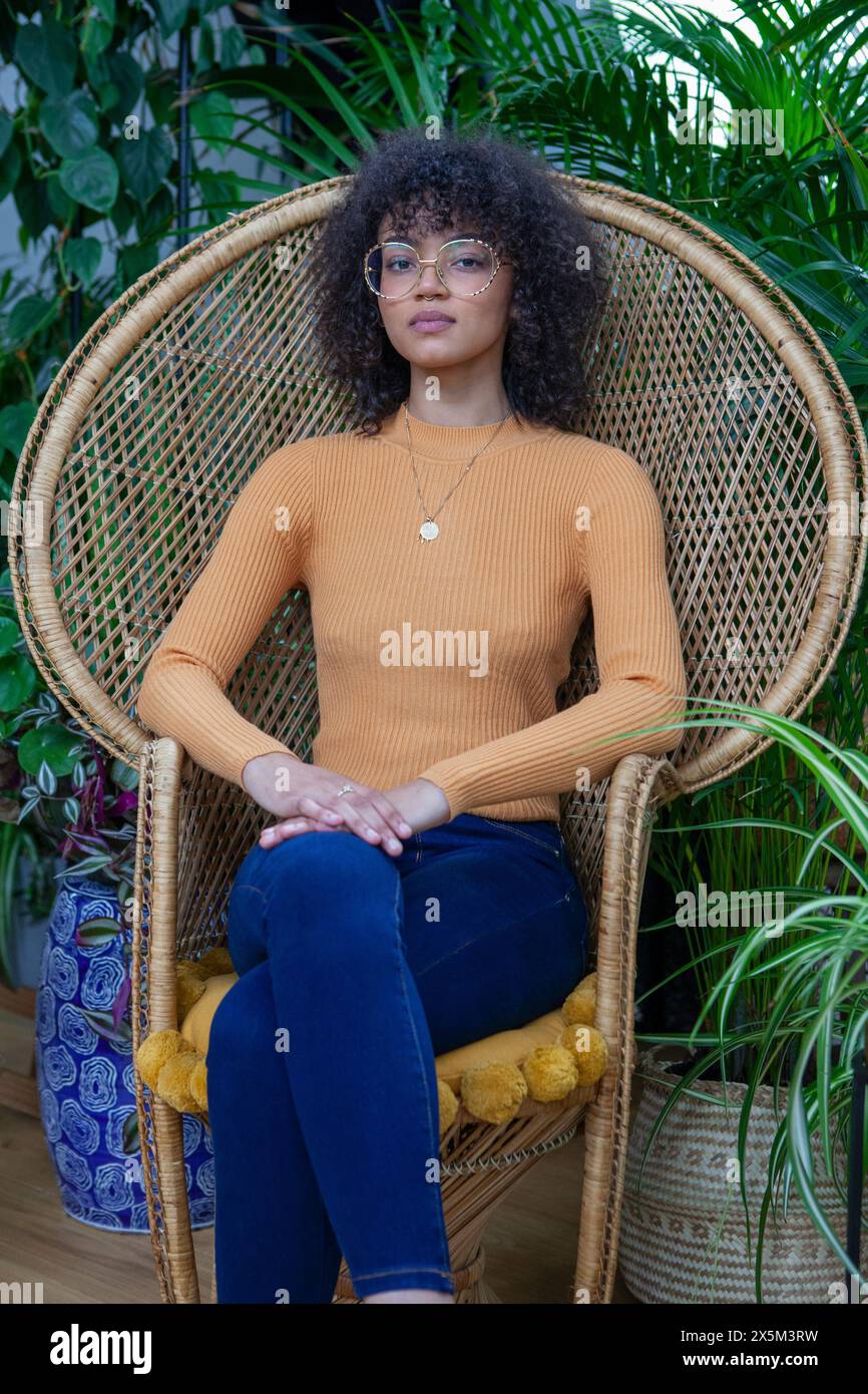 Portrait of woman sitting in tropical style rattan armchair Stock Photo ...