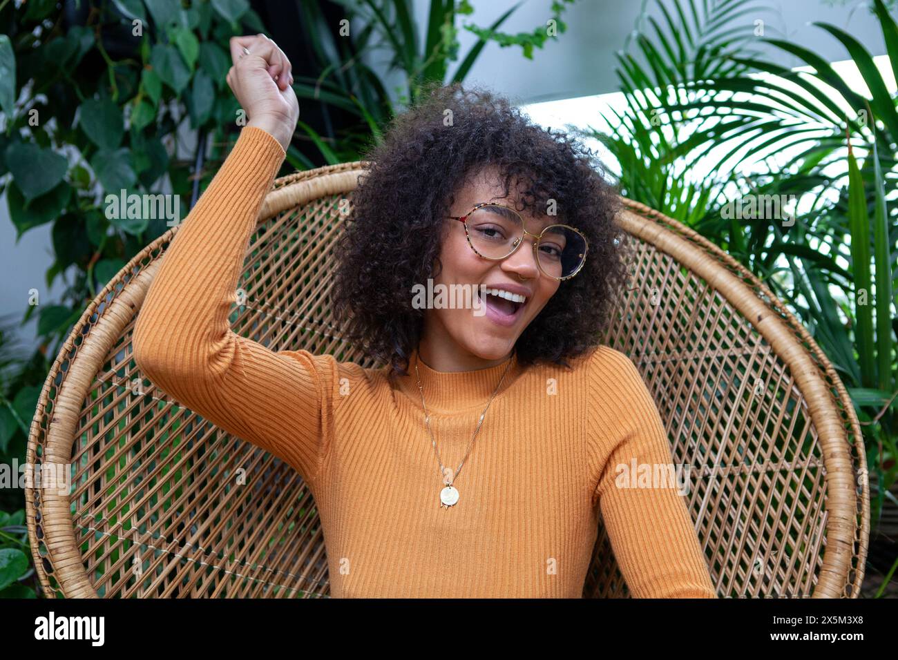 Portrait of smiling woman sitting in tropical style rattan armchair ...