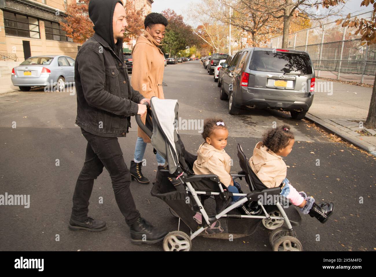 Parents walking in street with daughters in stroller Stock Photo - Alamy