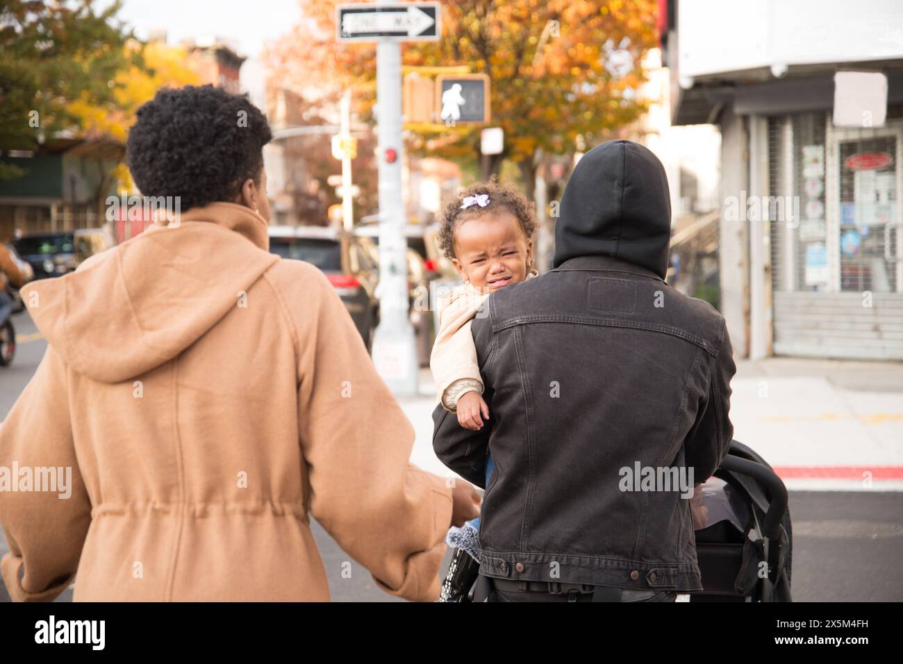 Parents with crying daughter walking in street Stock Photo - Alamy