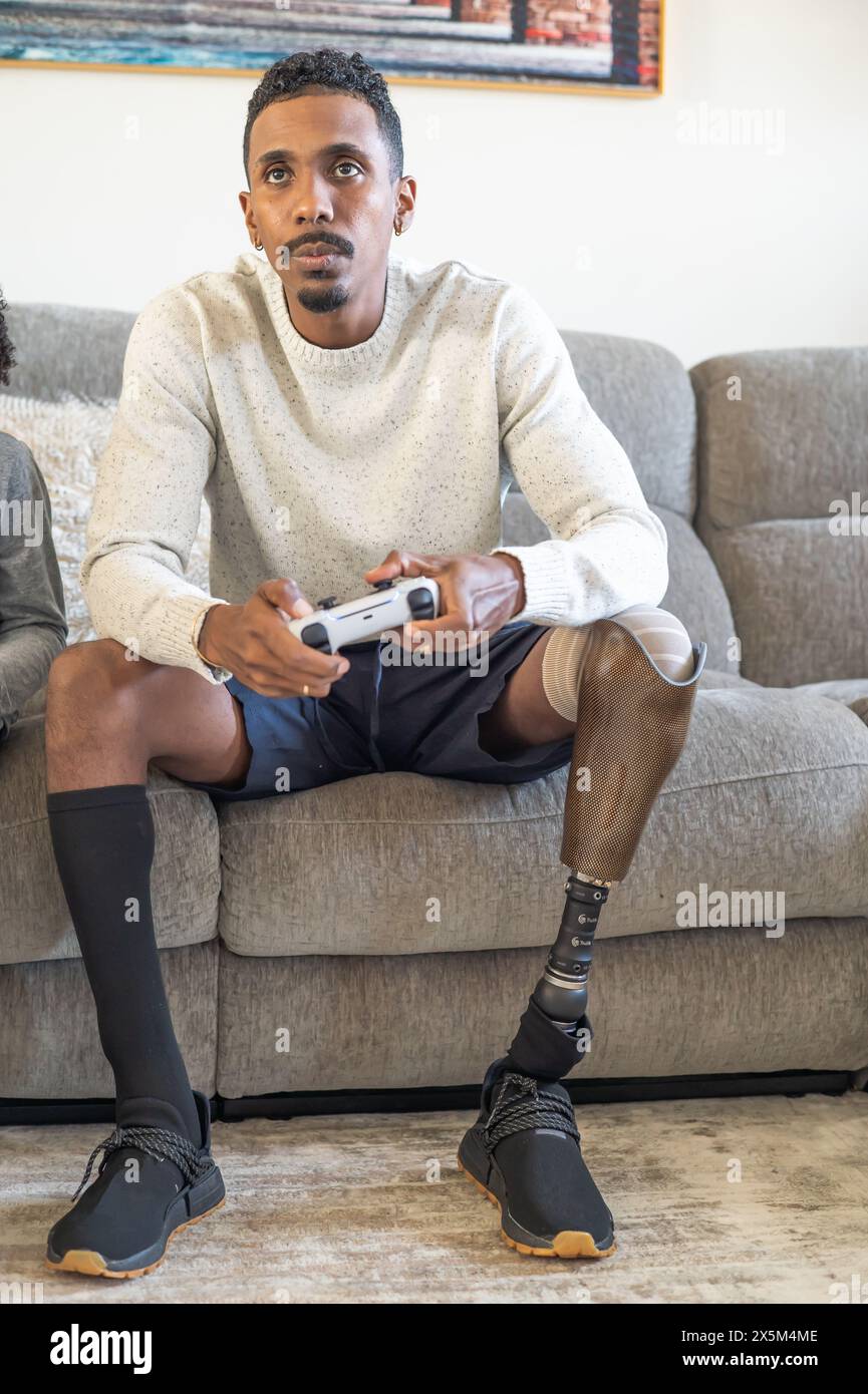 Man with prosthetic leg playing video game on sofa Stock Photo - Alamy