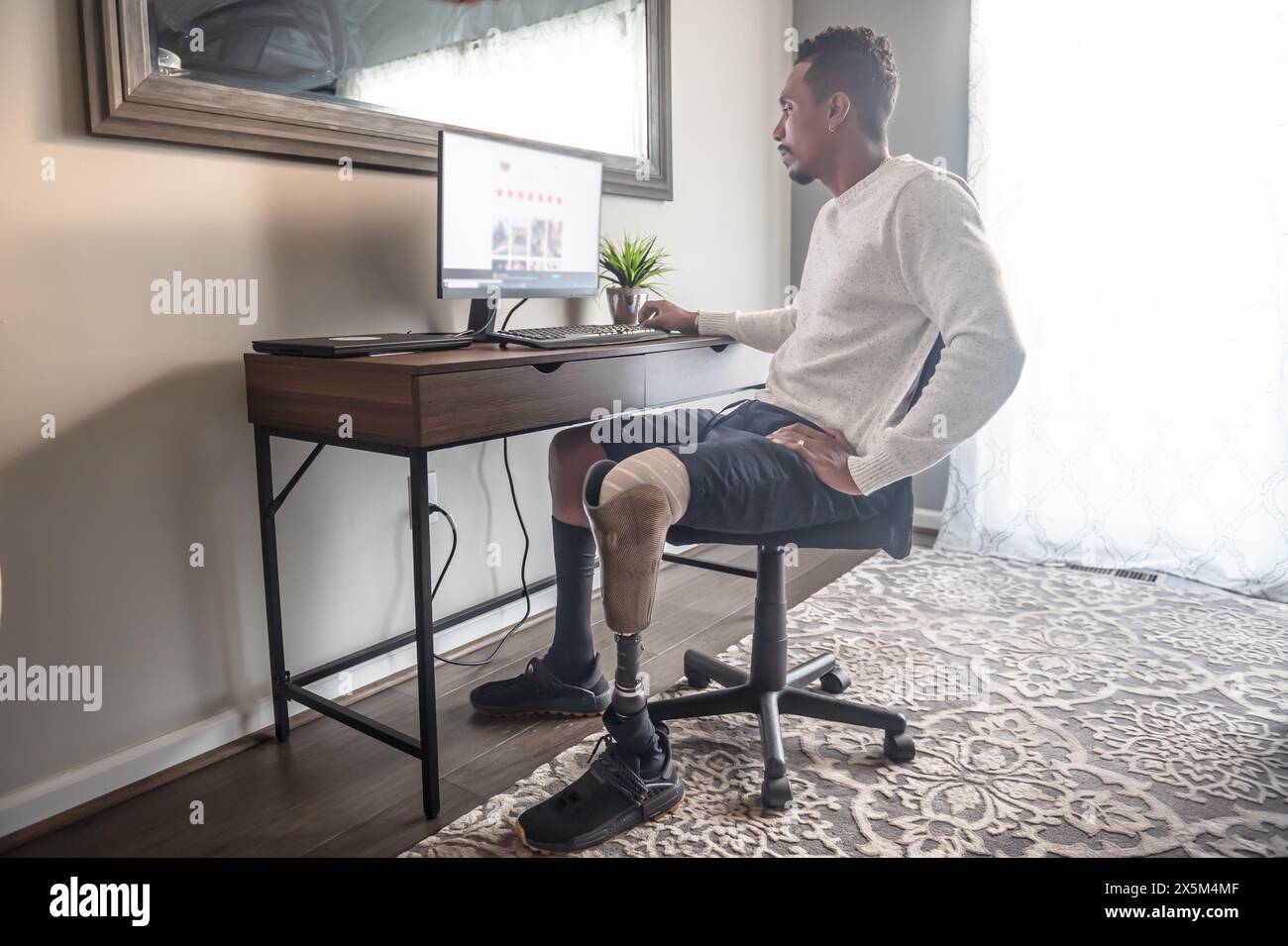 Man with prosthetic leg using computer at home Stock Photo - Alamy
