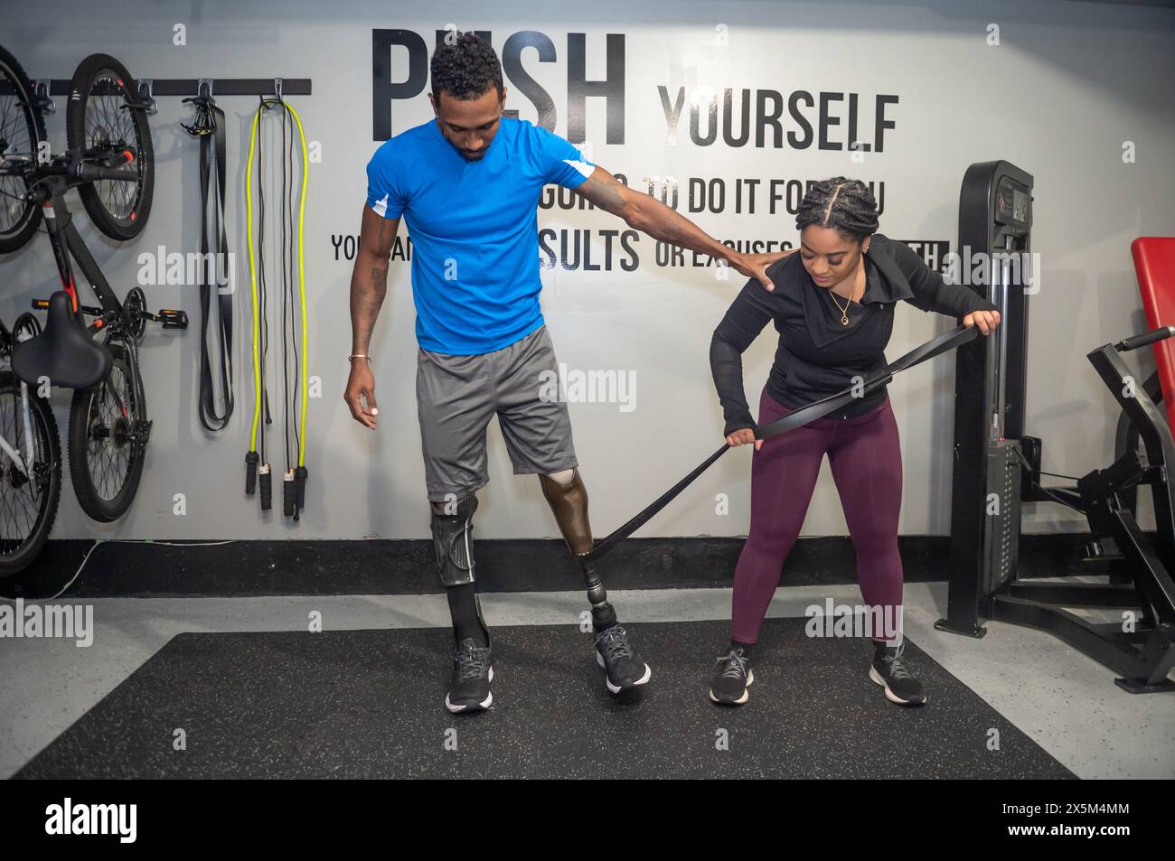Woman assisting man with prosthetic leg exercising in gym Stock Photo ...