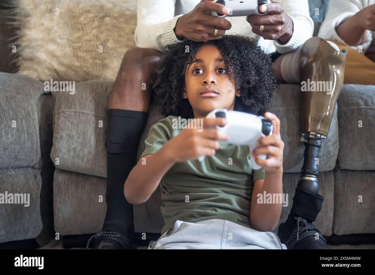 Boy playing video game with father with prosthetic leg Stock Photo - Alamy