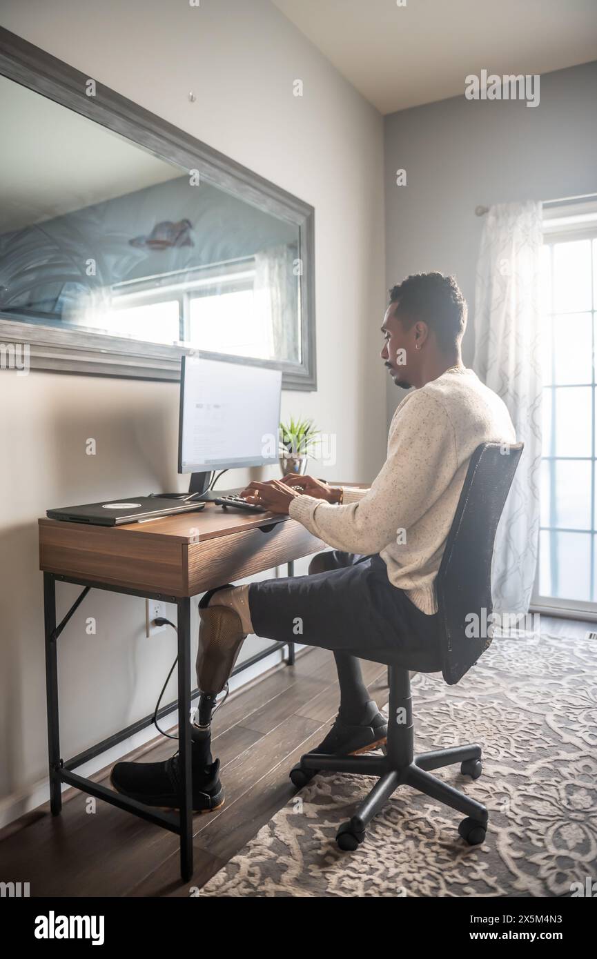 Man with prosthetic leg using computer at home Stock Photo - Alamy