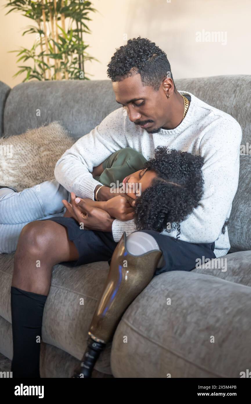 Man with prosthetic leg hugging son on sofa Stock Photo - Alamy