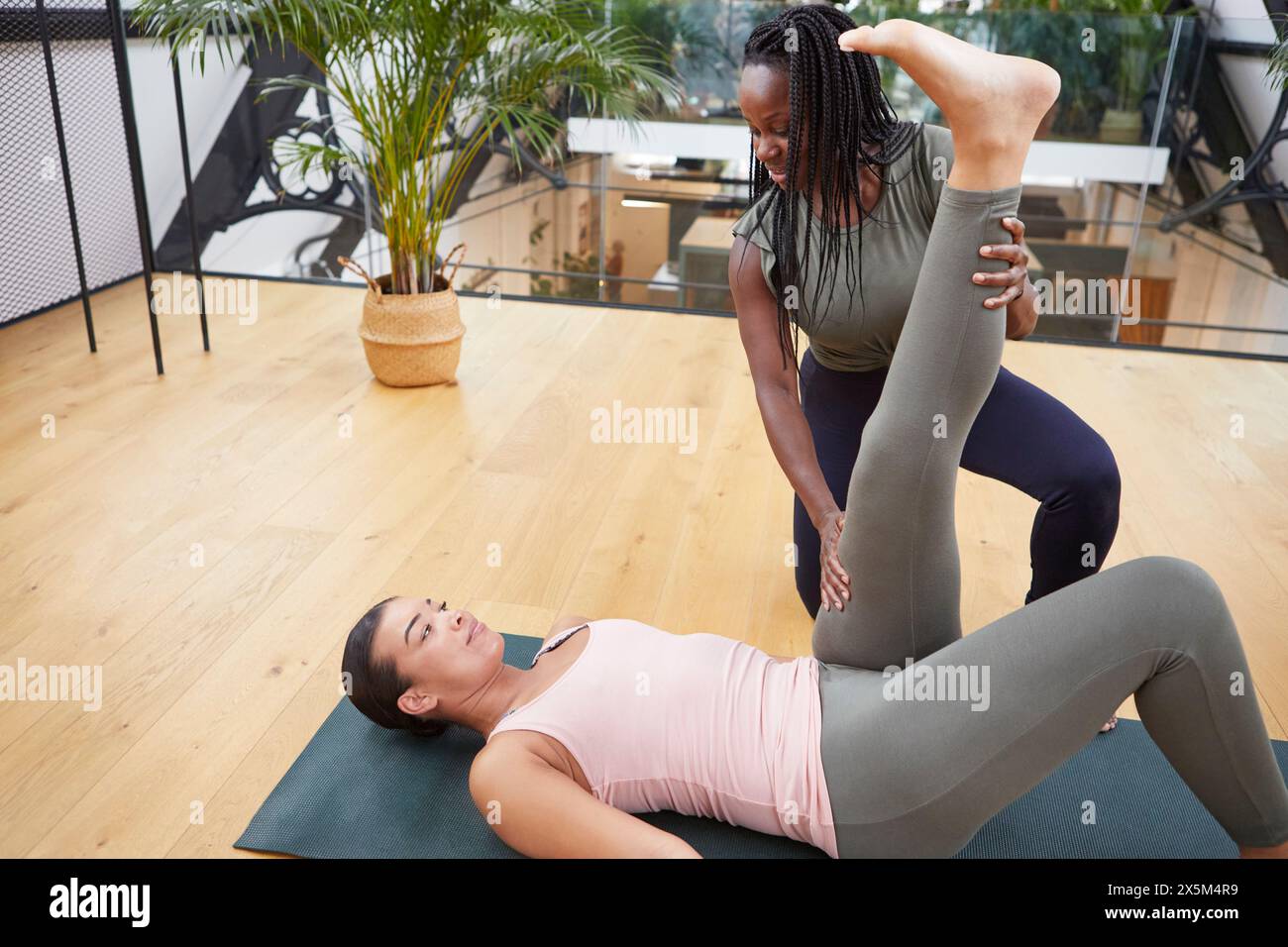 Female instructor assisting woman practicing pilates in studio Stock ...