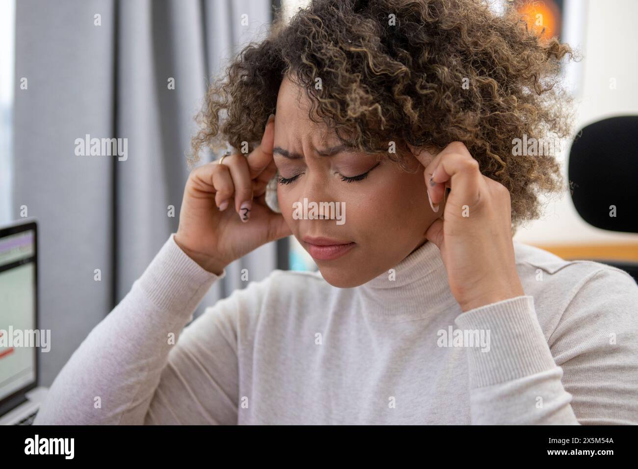 Woman rubbing temples with eyes closed Stock Photo - Alamy