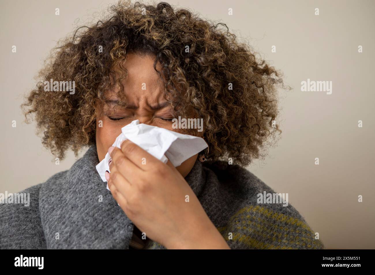 Woman wrapped in blanket blowing nose Stock Photo - Alamy