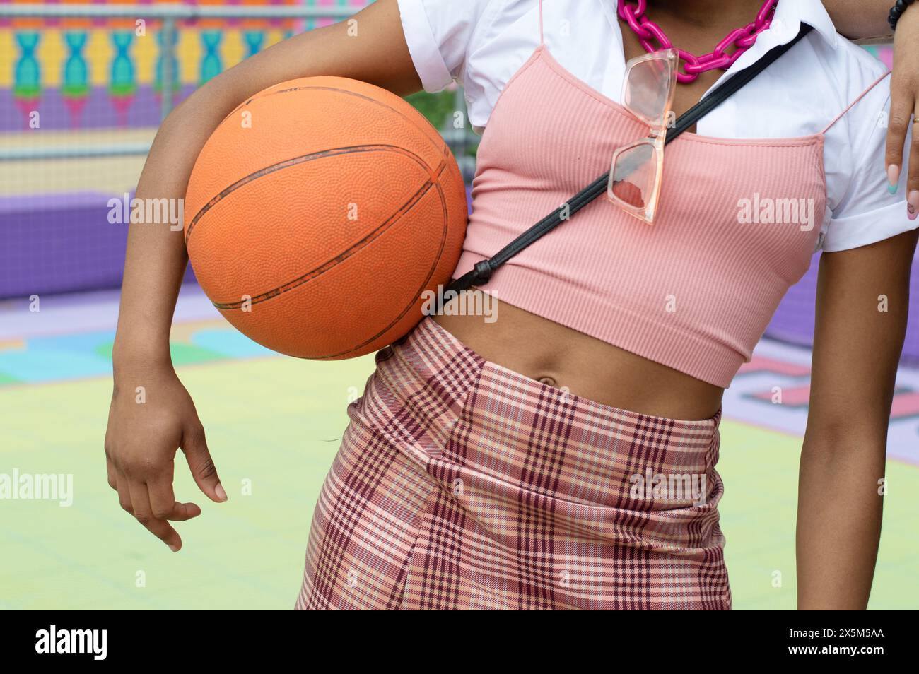 Mid section of young woman in crop top holding basketball ball Stock ...